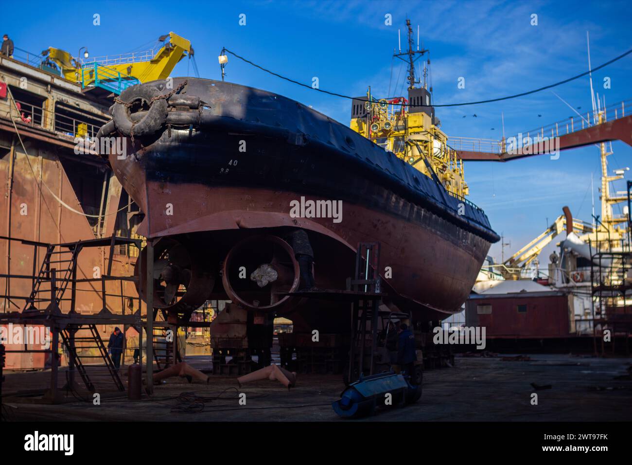 Fishing vessel maintenance in shipyard drydock. Workers repair, repaint ...