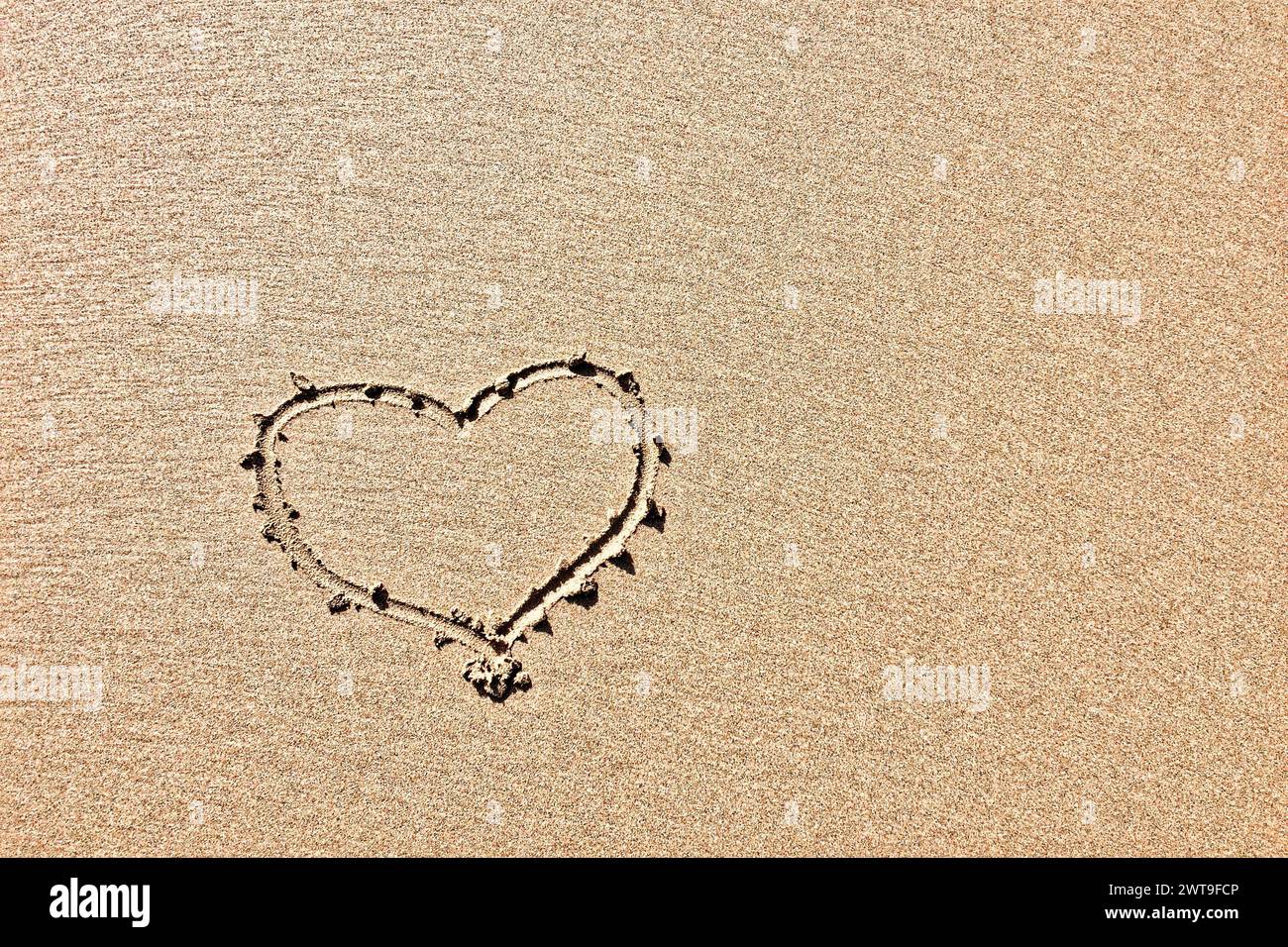 The photo captures a heart outline drawn in sand, highlighting its ...