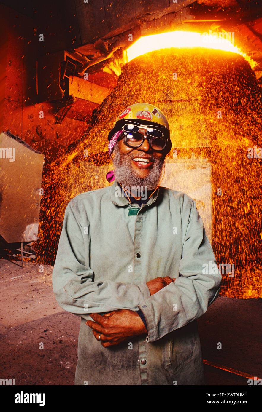 Steel worker pauses for a photograph next to a glowing hot blast ...