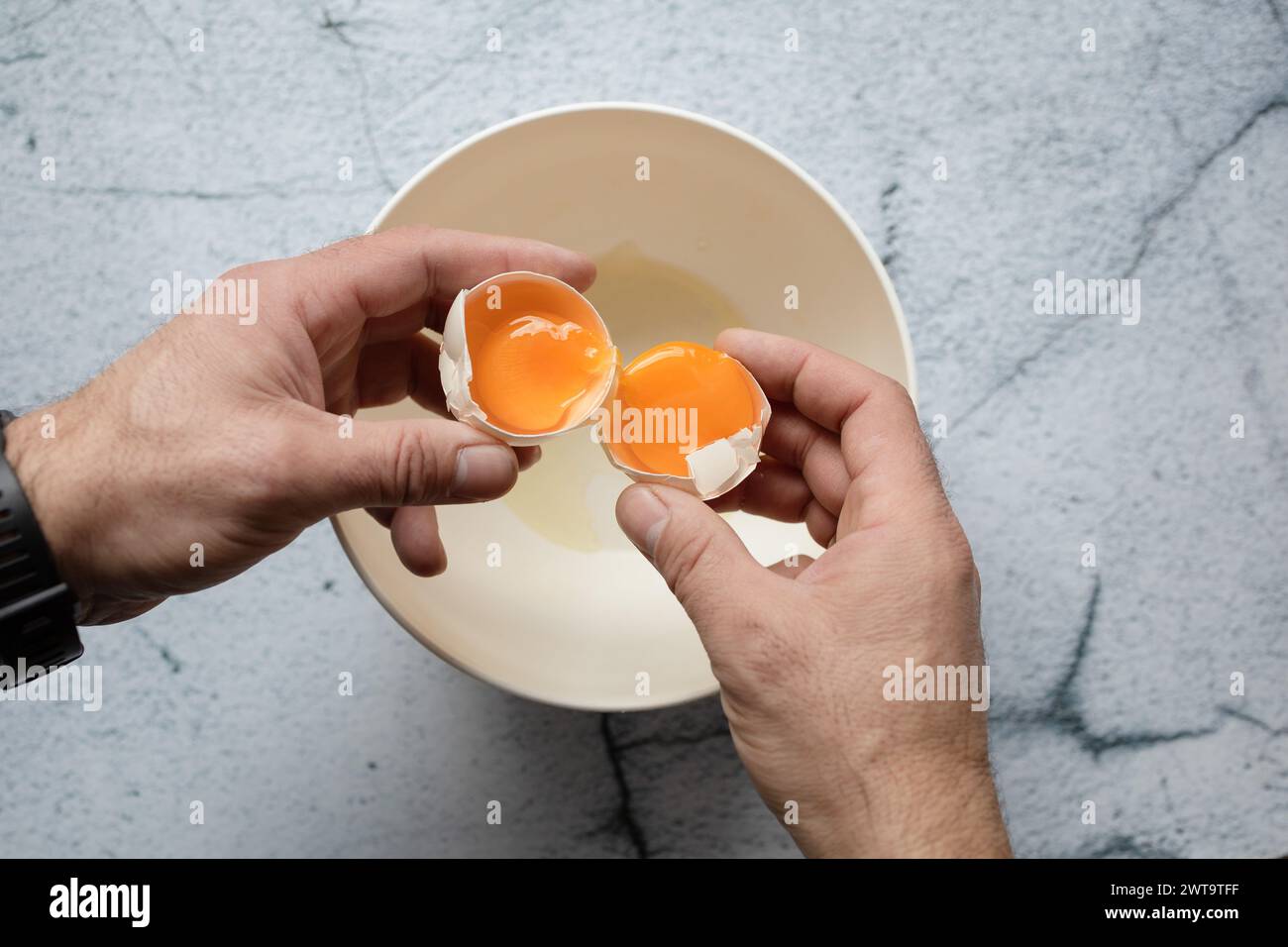 Hands cracking an egg with two yolks inside Stock Photo - Alamy
