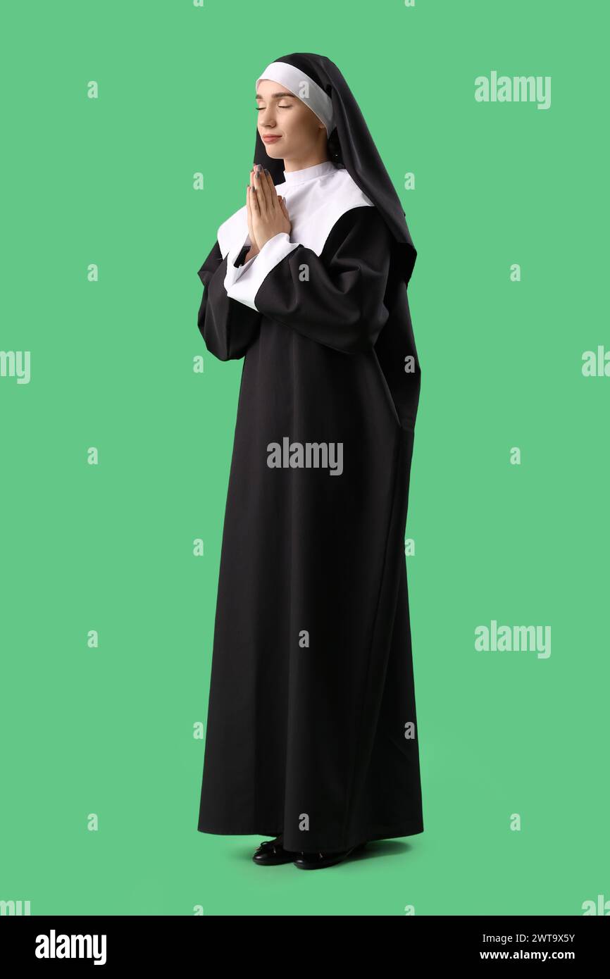 Portrait of praying nun on green background Stock Photo - Alamy