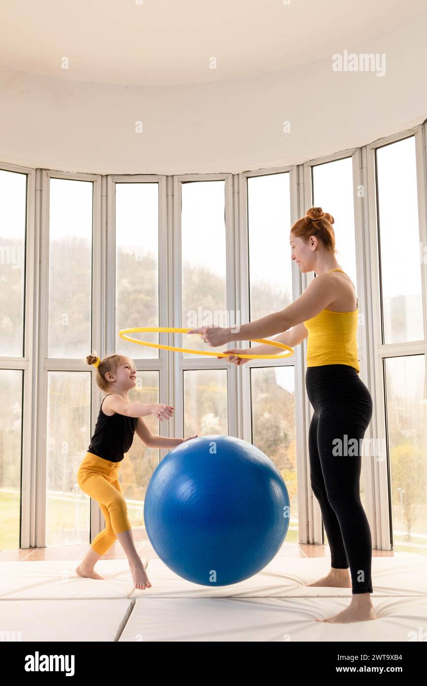 Young fit mom and her daughter having fun with hula hoop and fitness ...