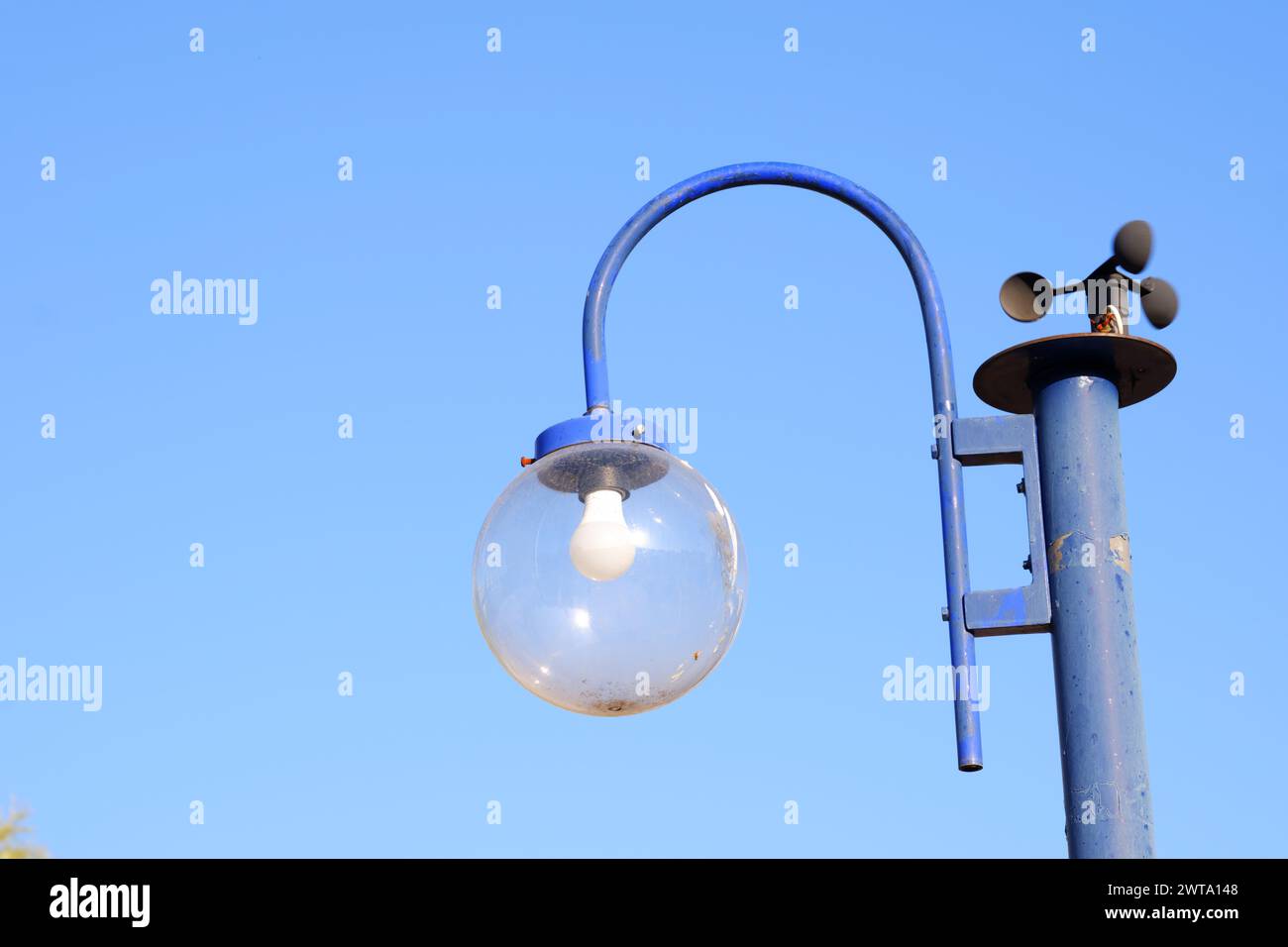 Blue street lamp with anamometer with blue sky at the background in a ...