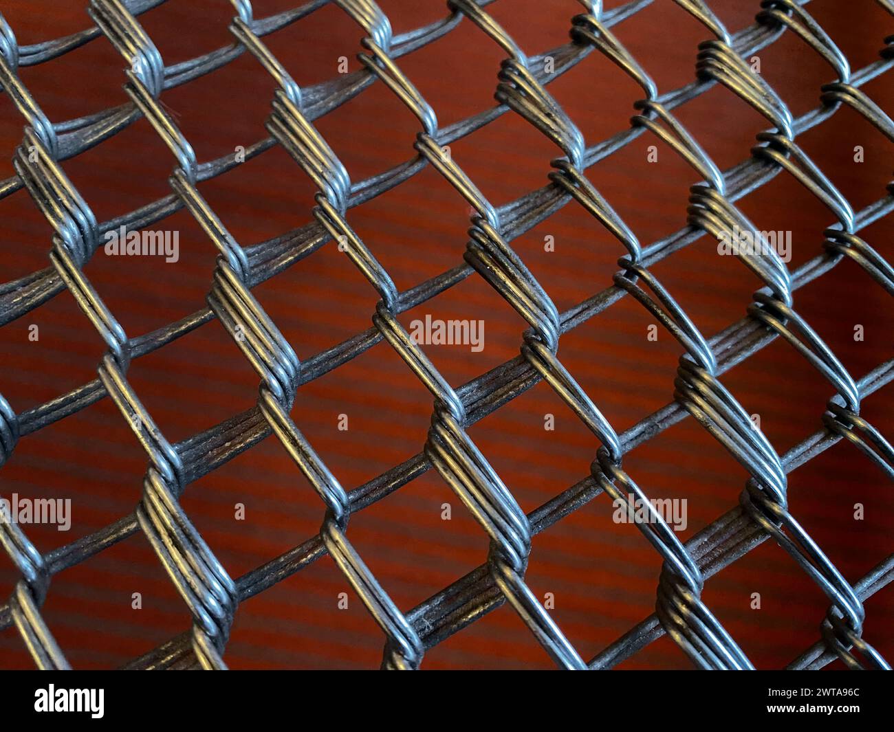 Texture of metal grid with cells on the red background, selective focus ...