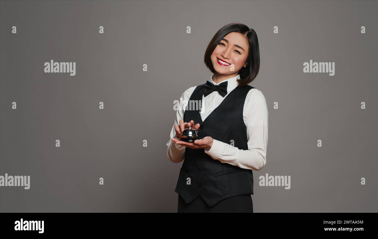 Woman hotel employee ringing front desk service bell in studio, working ...