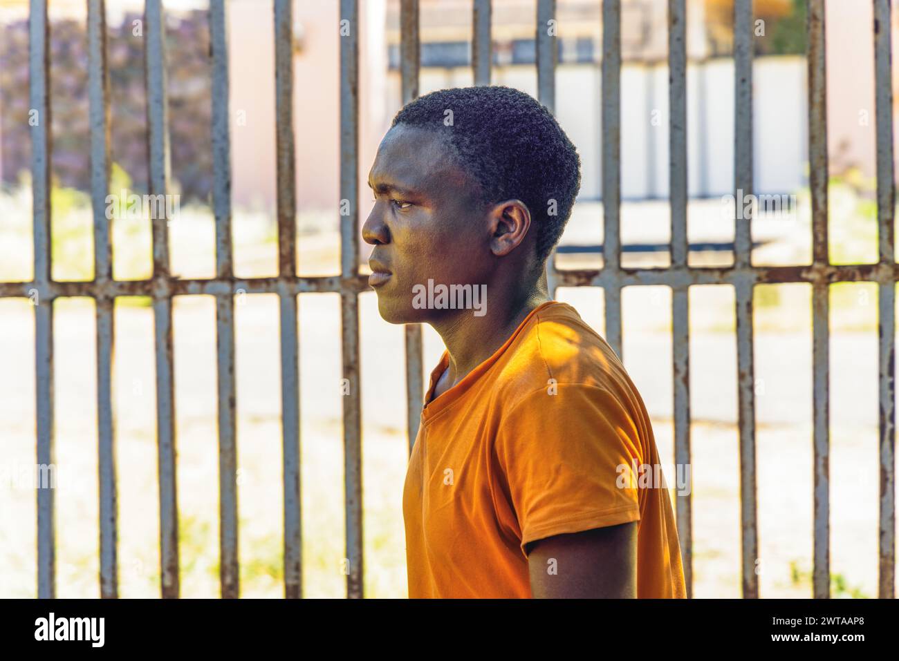 african man standing in front of burglar bars, he got a with a manly ...