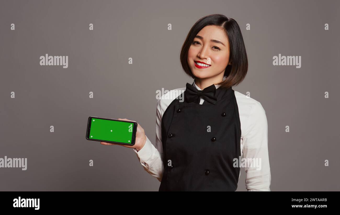 Catering employee holding phone with greenscreen display, pointing at ...