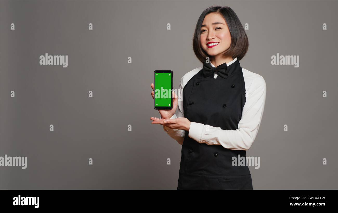 Restaurant hostess presenting smartphone with greenscreen, showing ...