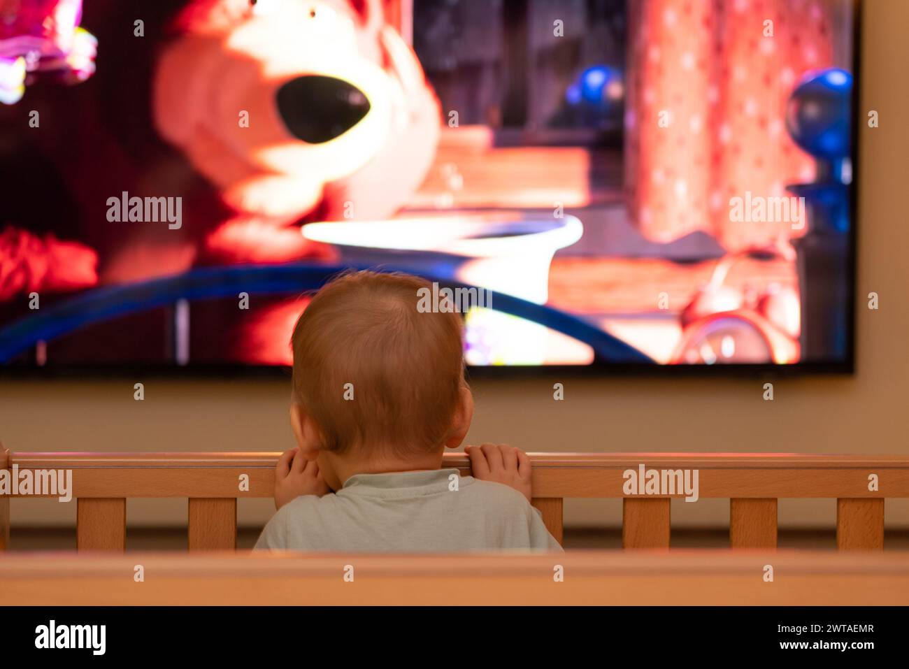 On the TV screen there are cartoons watched by a small child from a ...