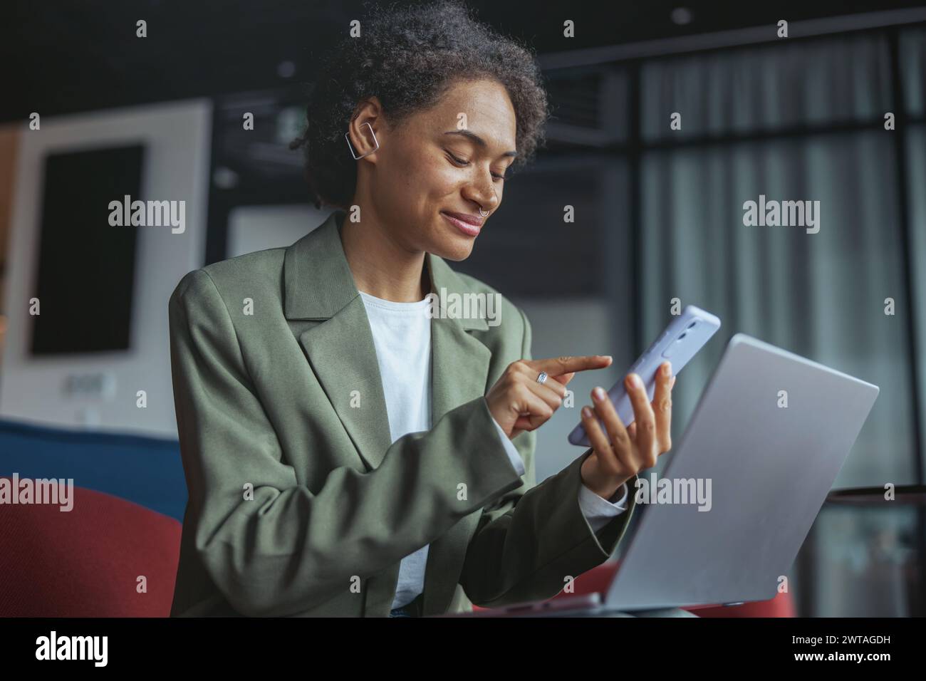 TV presenter in formal wear smiling, using laptop and cell phone at ...