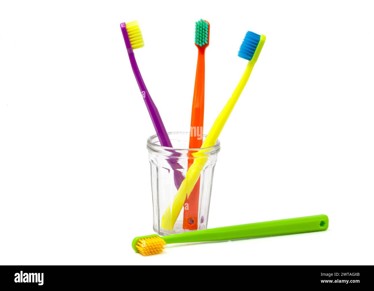 Three toothbrushes - purple, orange and yellow with multi-coloured ...