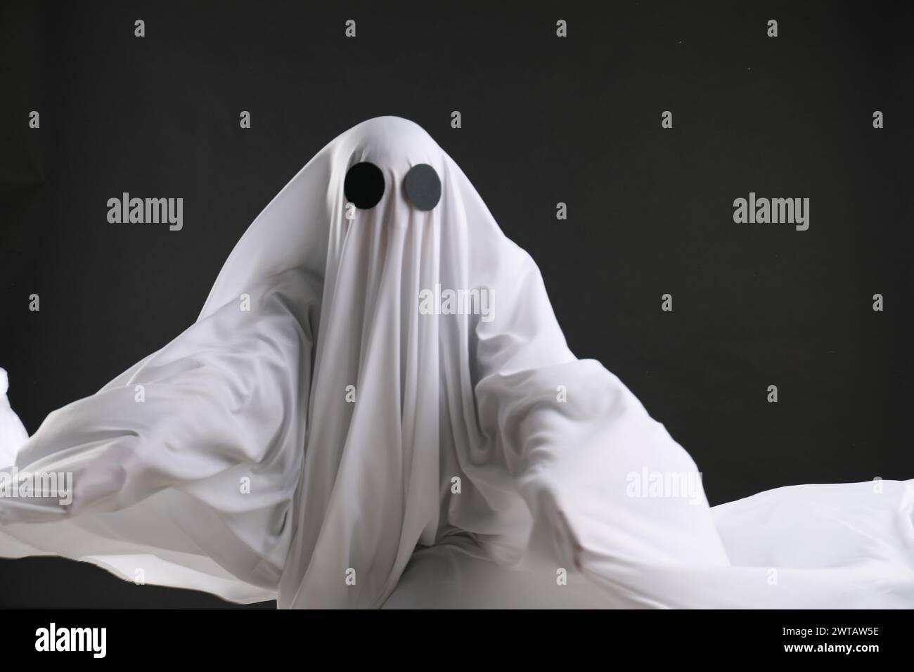 Creepy ghost. Person covered with white sheet on black background Stock ...