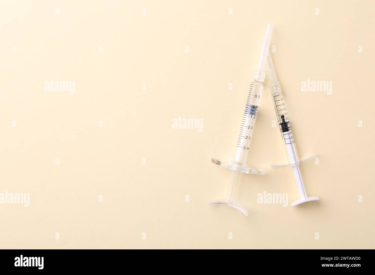 Injection cosmetology. Two medical syringes on beige background, top ...