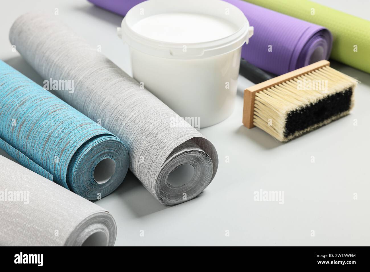 Different wallpaper rolls, brush and bucket with glue on light ...