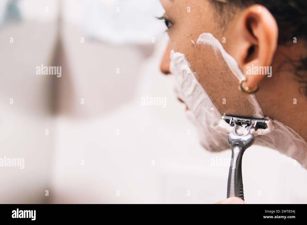 A young Latino man carefully shaving his face with a razor, detailed ...