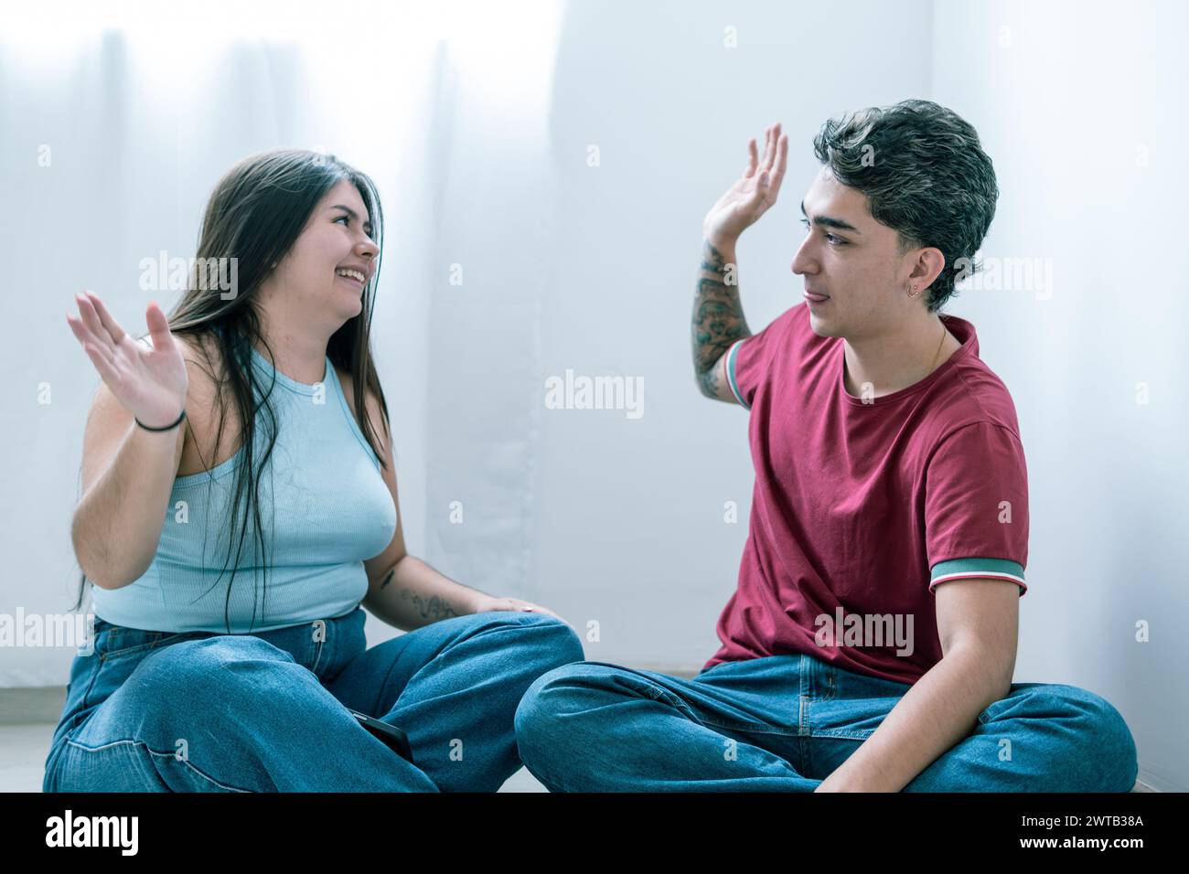 An excited young Latino couple about to high-five, sharing a joyful and ...
