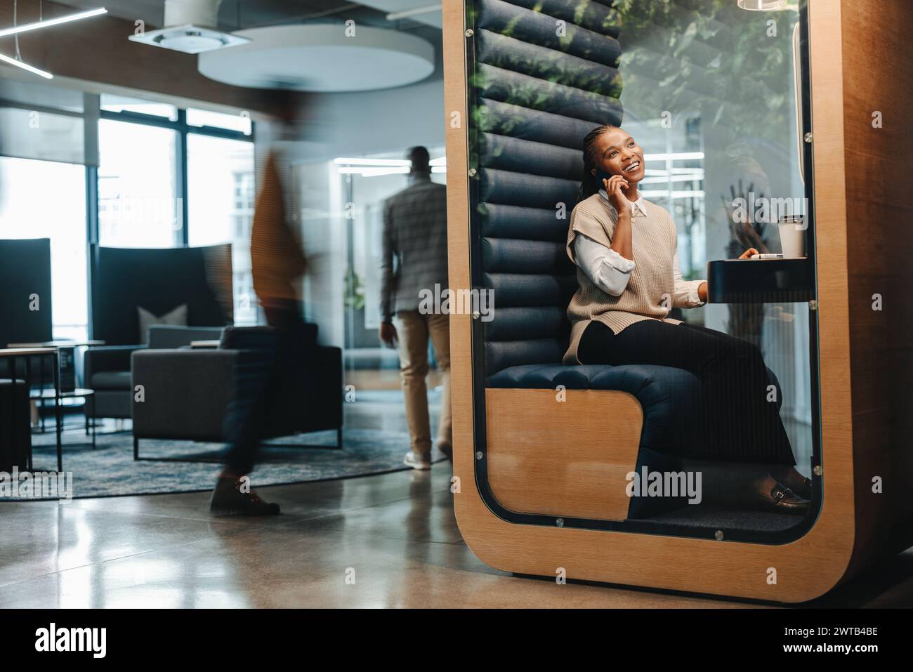 Happy businesswoman sitting in a coworking space, speaking on her ...