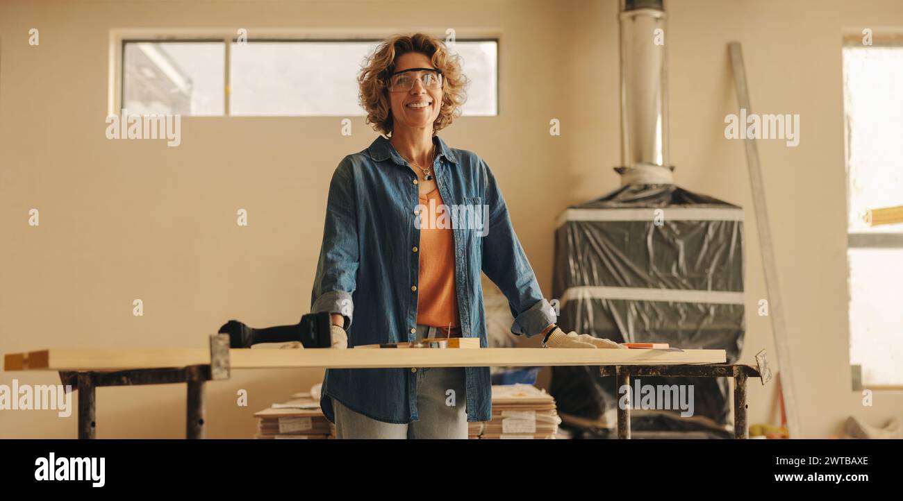 Mature, skilled woman with safety goggles remodels a kitchen with wood ...