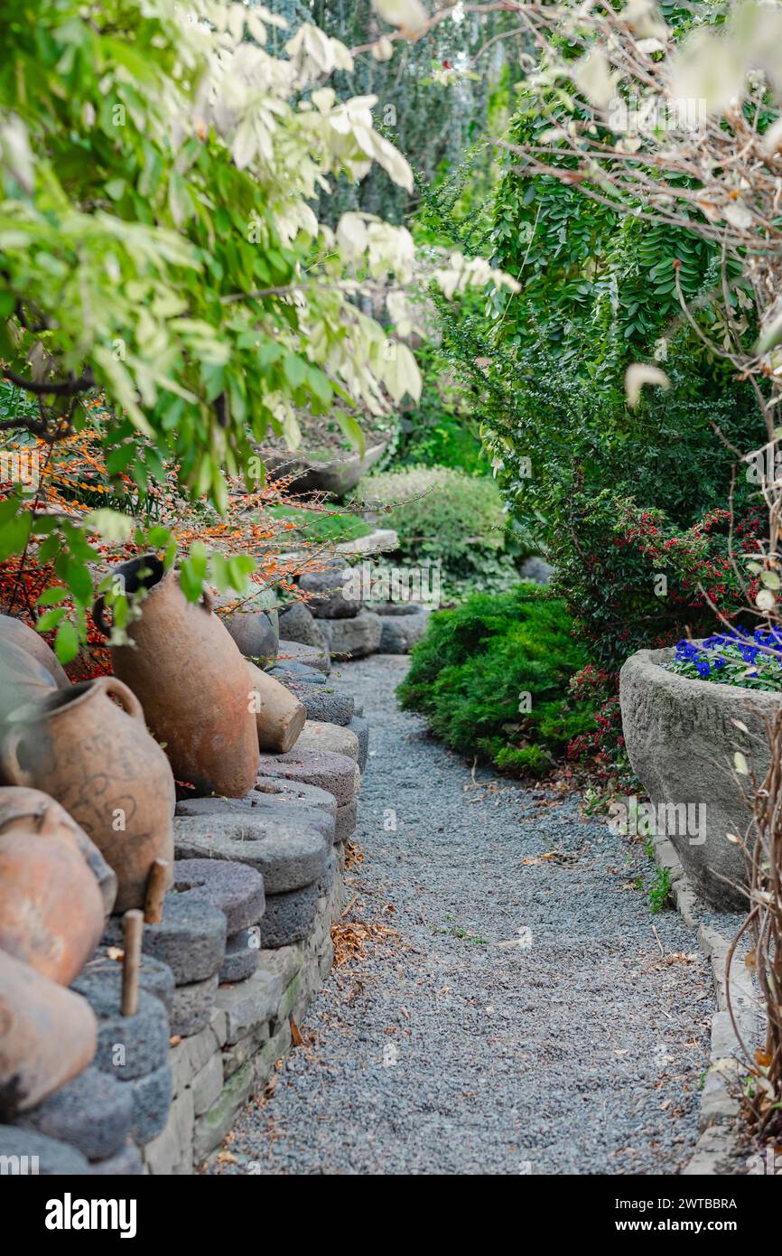 A serene gravel path meanders through a lush garden, flanked by antique ...