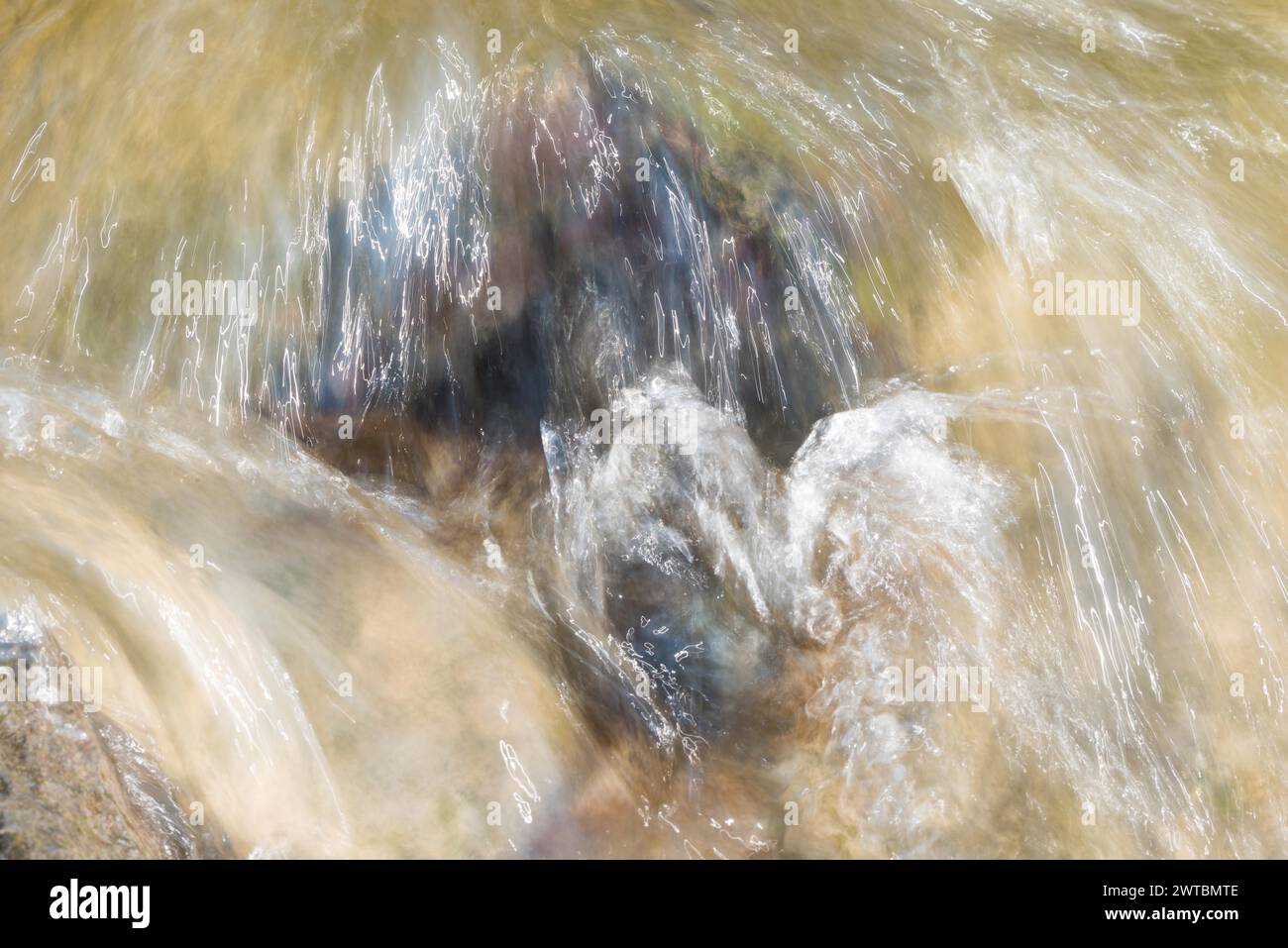 Moving water flows over a boulder, rapids, motion blur conveys the flow ...