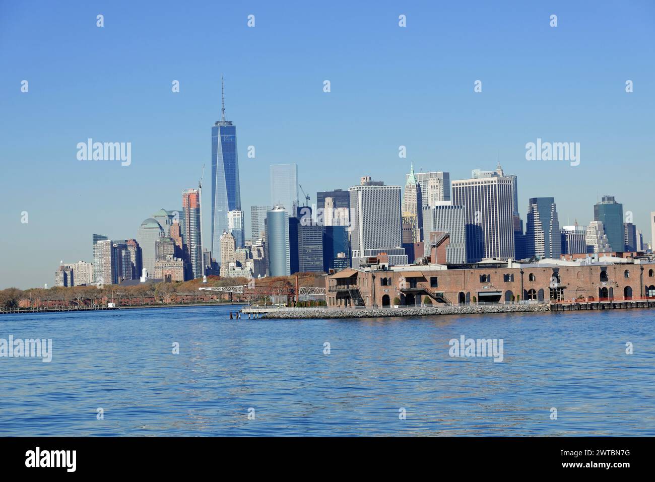 Skyline on the water under a clear blue sky with reflections on the water surface, Manhattan ...