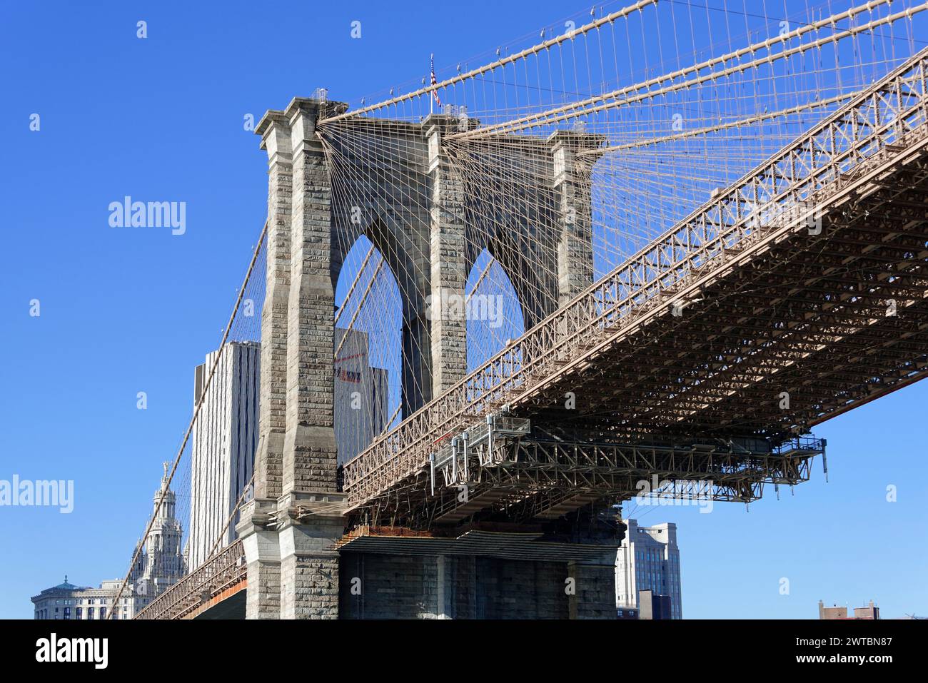 The Brooklyn Bridge from below with a clear blue sky in the background ...