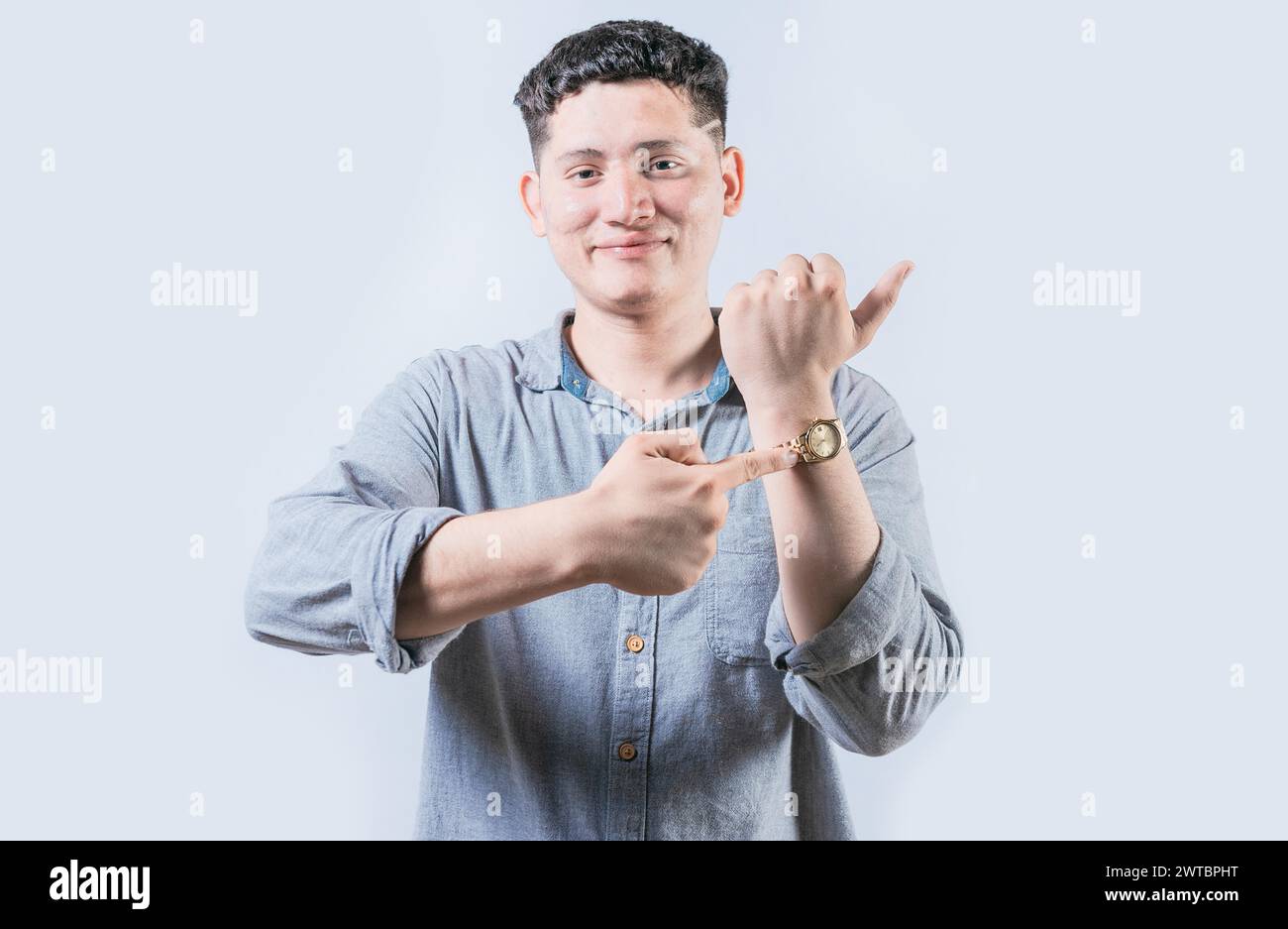 Smiling young man pointing at his wrist watch isolated. Portrait of ...