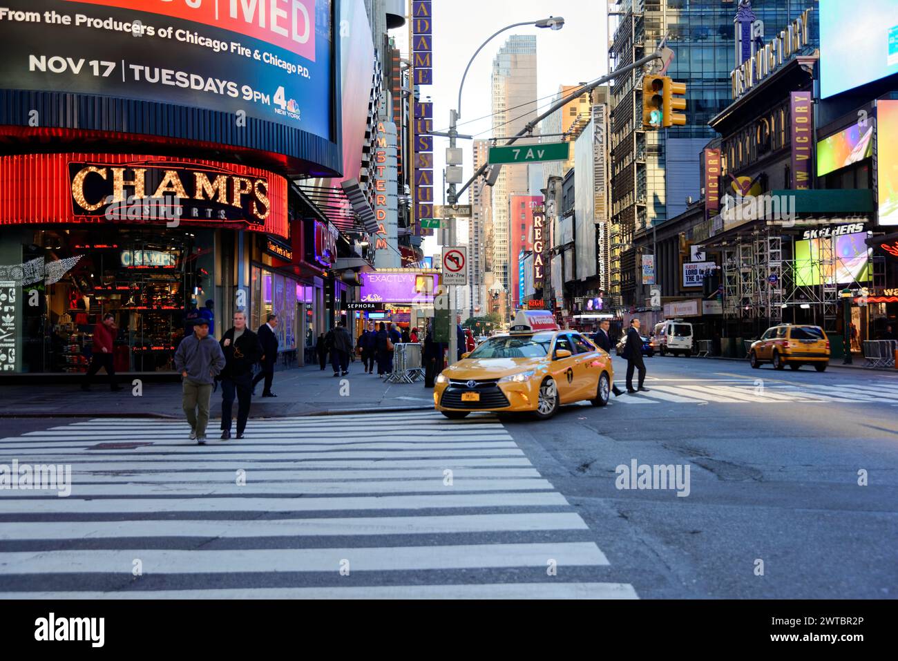 Busy urban intersection with taxi, pedestrians and advertising signs ...