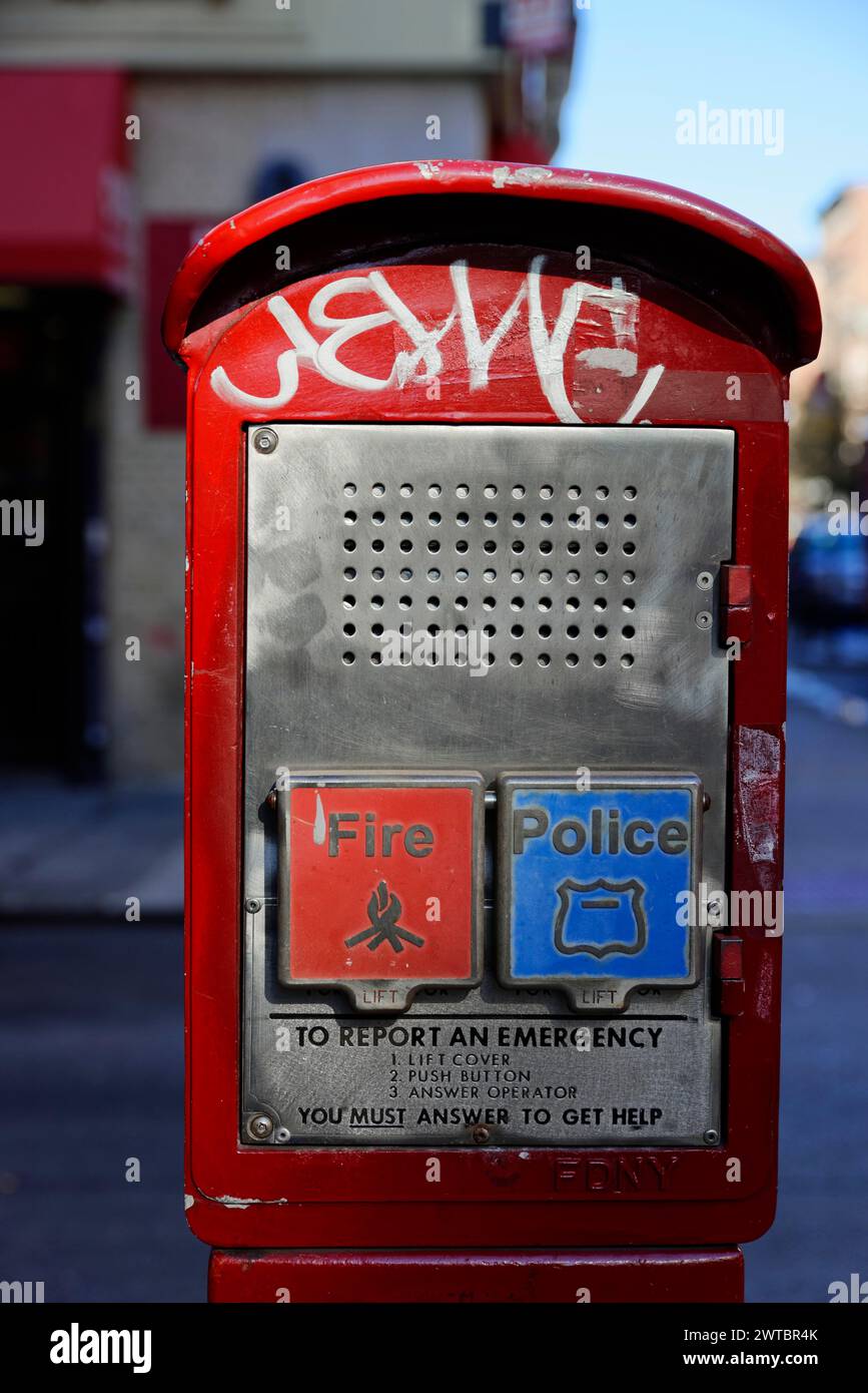 A red emergency call pillar with fire brigade and police signs, daubed ...