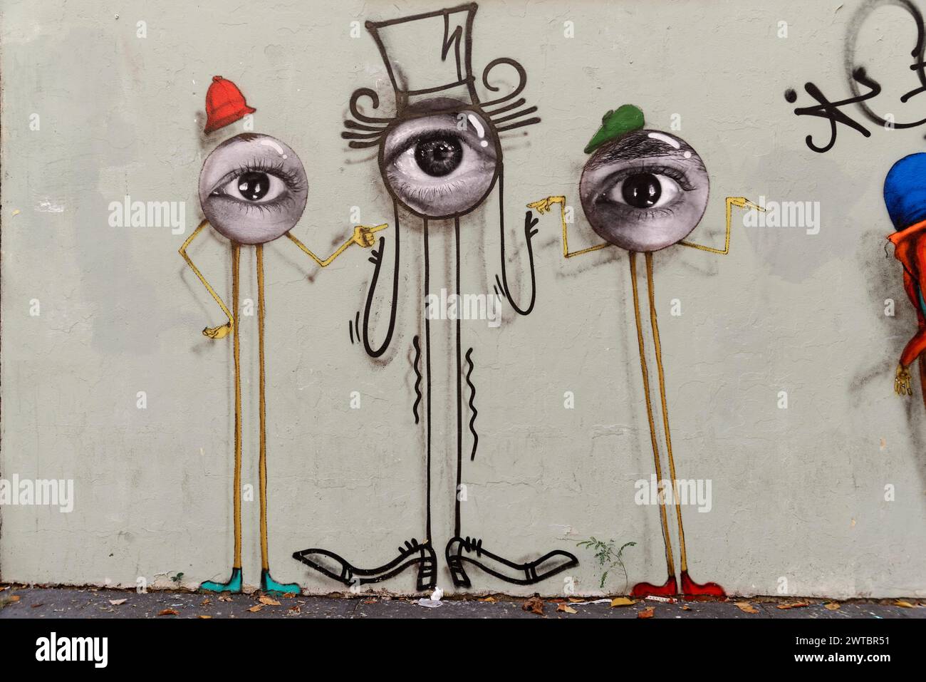 Identical artwork with long-legged figures with eyes and caps on a wall ...