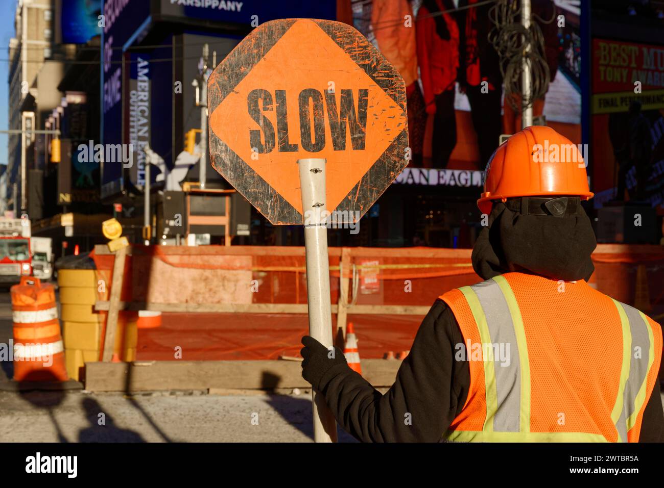 Construction worker in orange safety waistcoat holding a SLOW warning ...