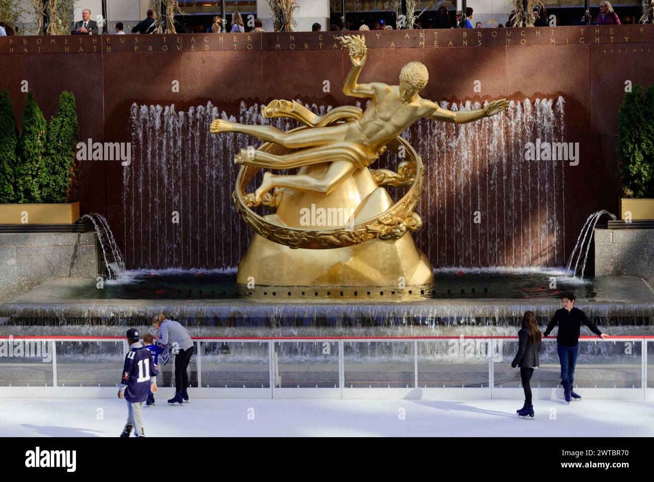 Golden Prometheus statue monitors ice skaters on a sunny day, Manhattan ...