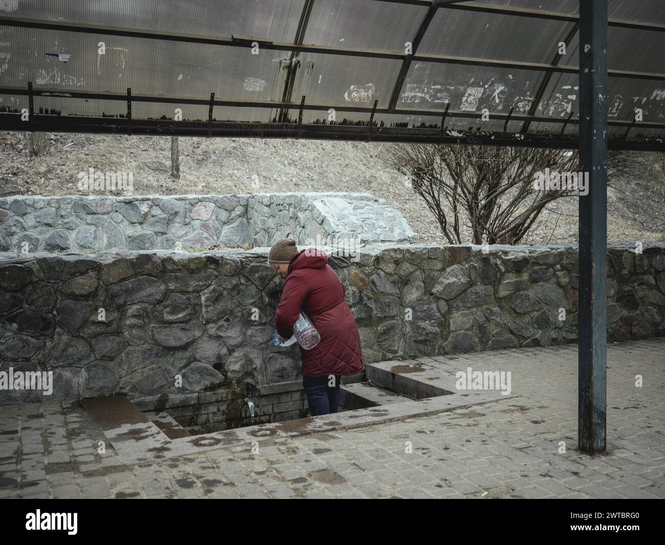 A woman fills drinking water at a public well. In the northern and ...