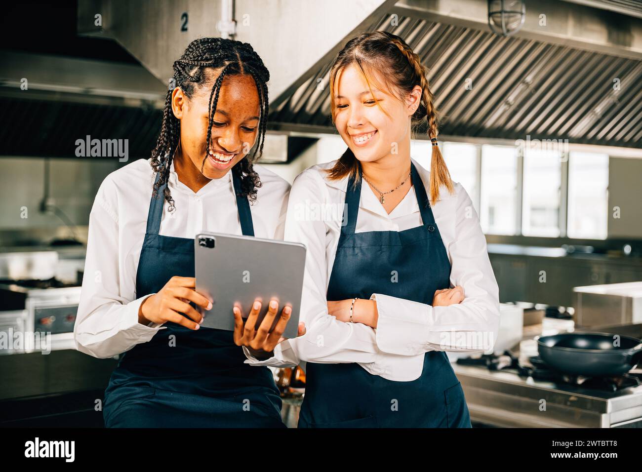 Two famous chefs in stainless steel kitchen discuss video blog using ...