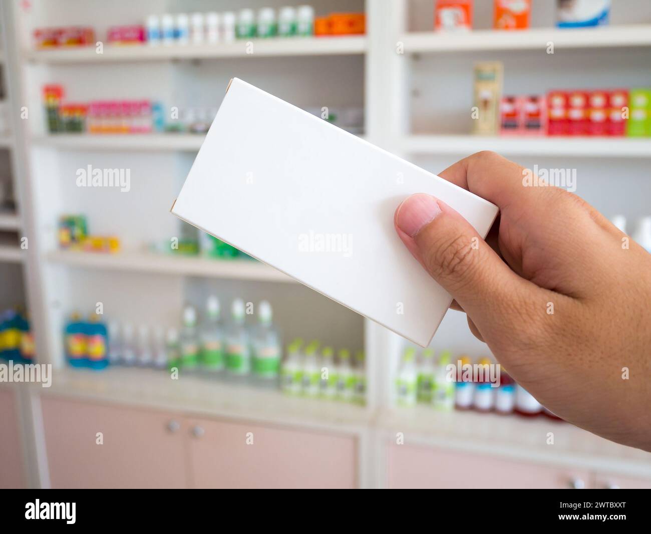 Close up pharmacist hand hold medicine box package with shelves of ...