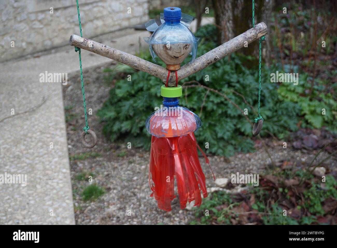 closeup on a recycled plastic bottle as a doll hanging like a swing in ...