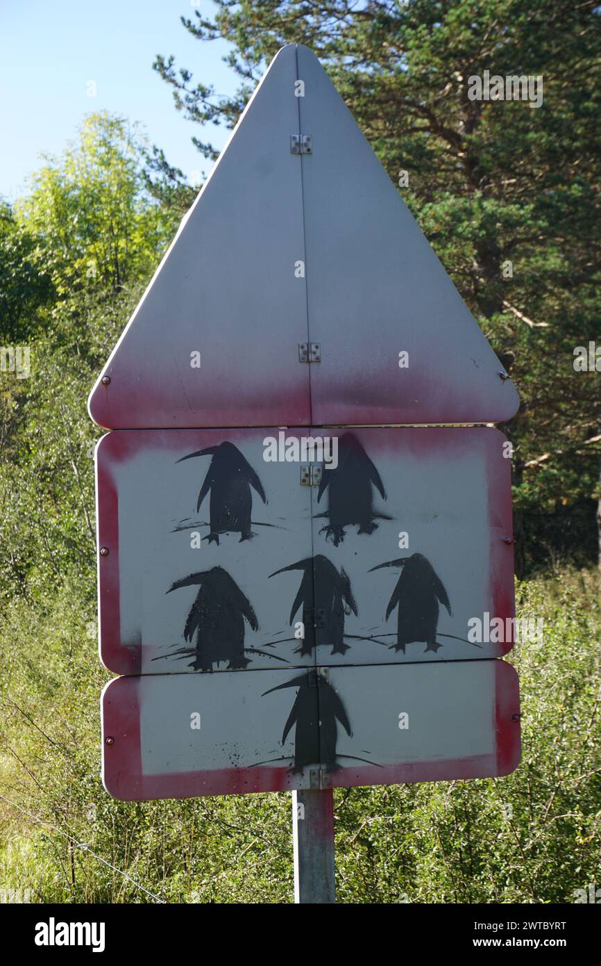closeup on a road sign painted and changed to black penguins in the ...