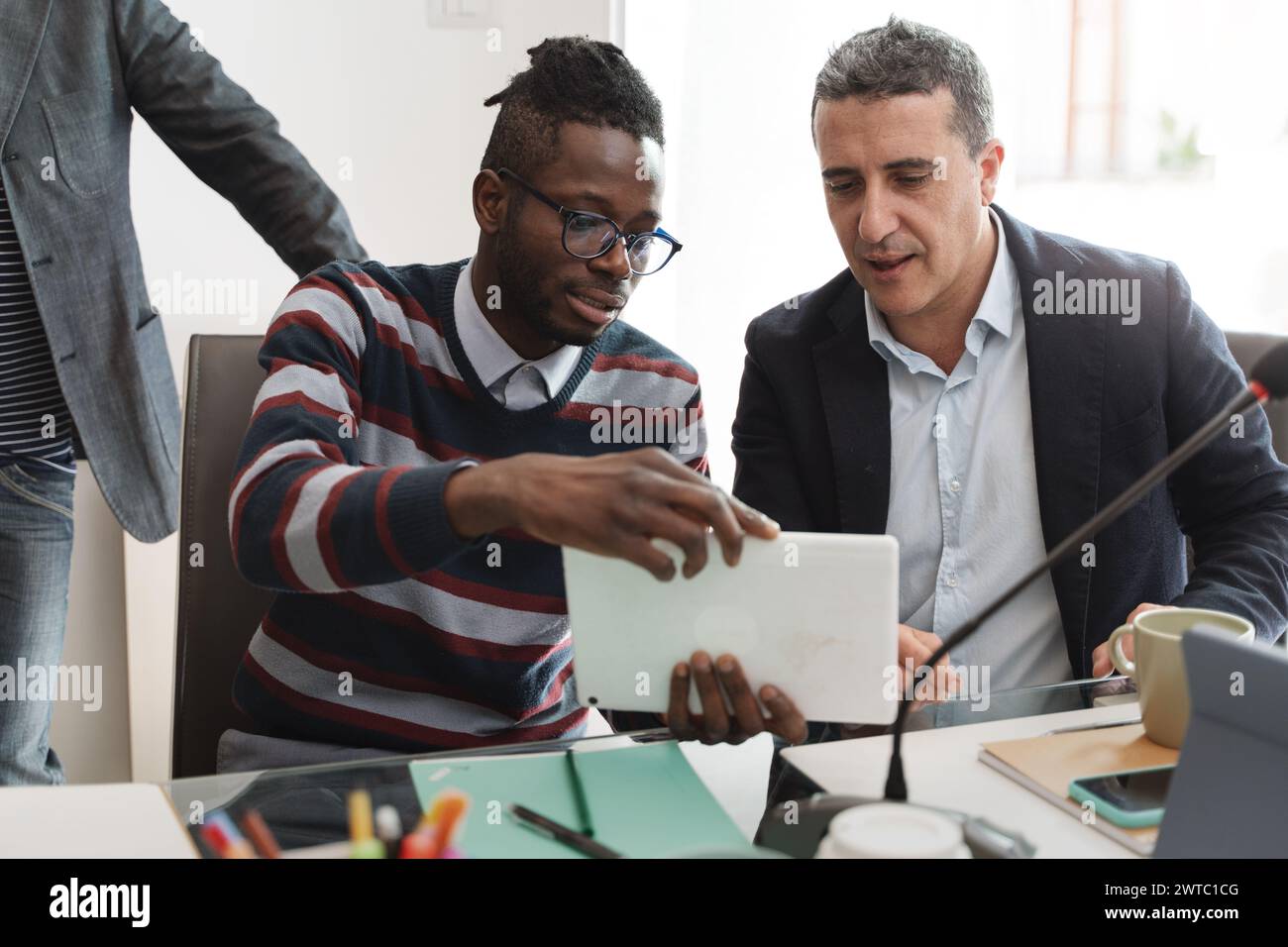 Two coworkers intently discuss work on a tablet, illustrating effective ...