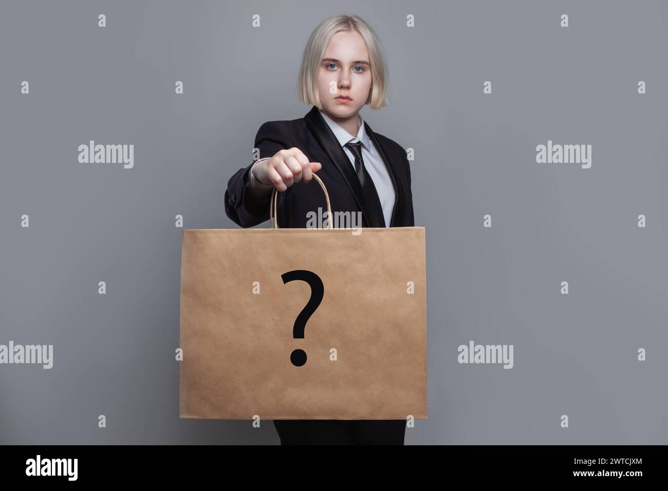 Pretty woman with shopping bag with question mark on grey background ...