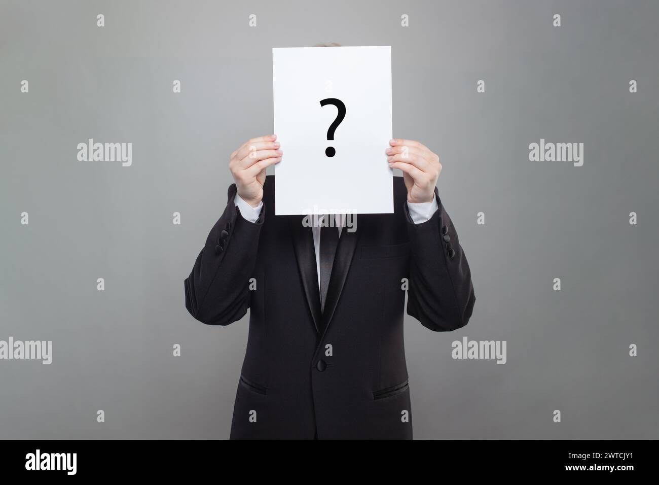 Business man wearing black suit hiding his face behind white paper with ...