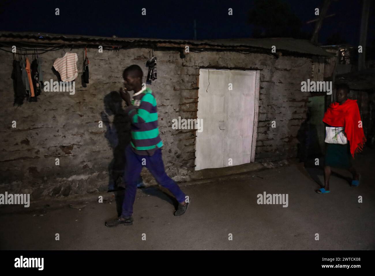 Residents walk past the dark streets in Kibera Slum headed for their ...