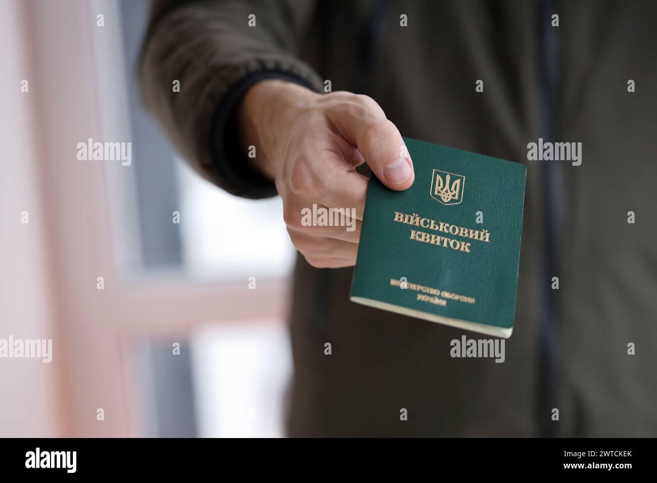 Young ukrainian conscript soldier shows his military token or army ID ...