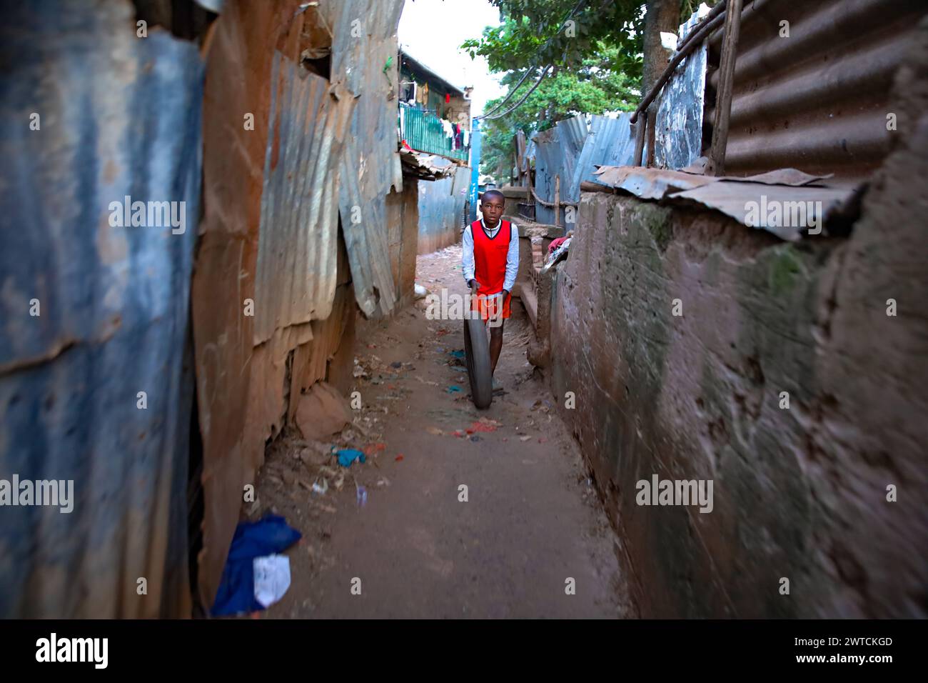 A young boy pushes a tyre past the corridors in Kibera Slum. Kibera ...