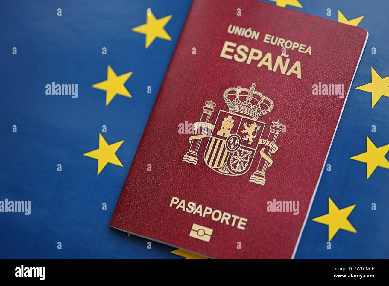 Red Spanish passport of European Union on blue flag background close up ...
