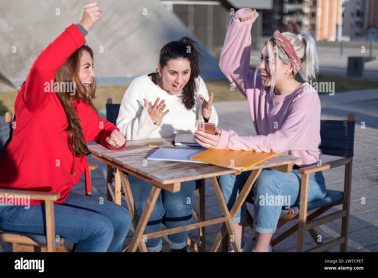 Three young women gather around a tablet and documents, engaged in a ...