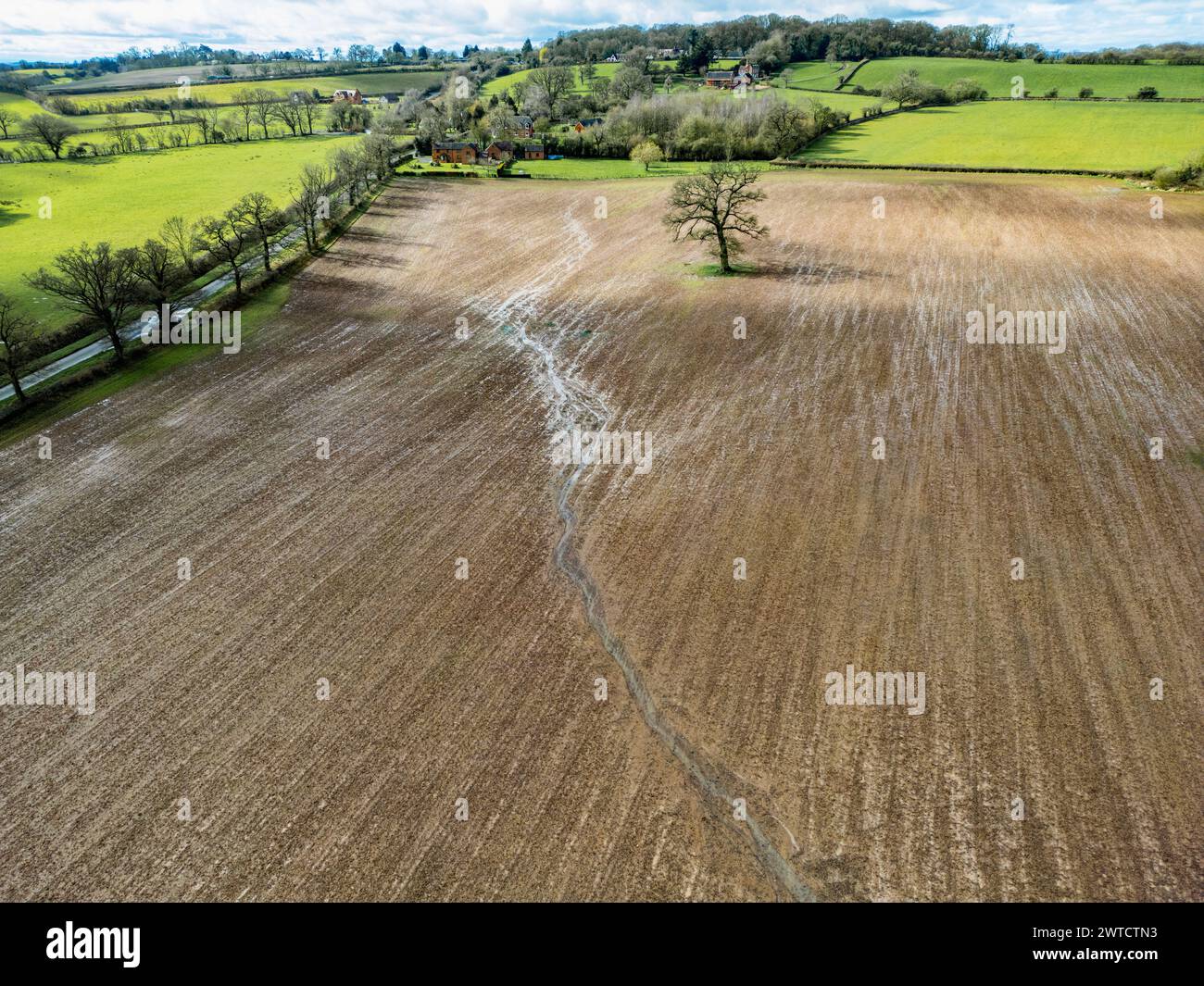A stream of rain water flows across a ploughed field after torrential ...