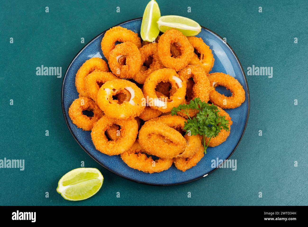 Baked breaded calamari rings served with lime Stock Photo - Alamy