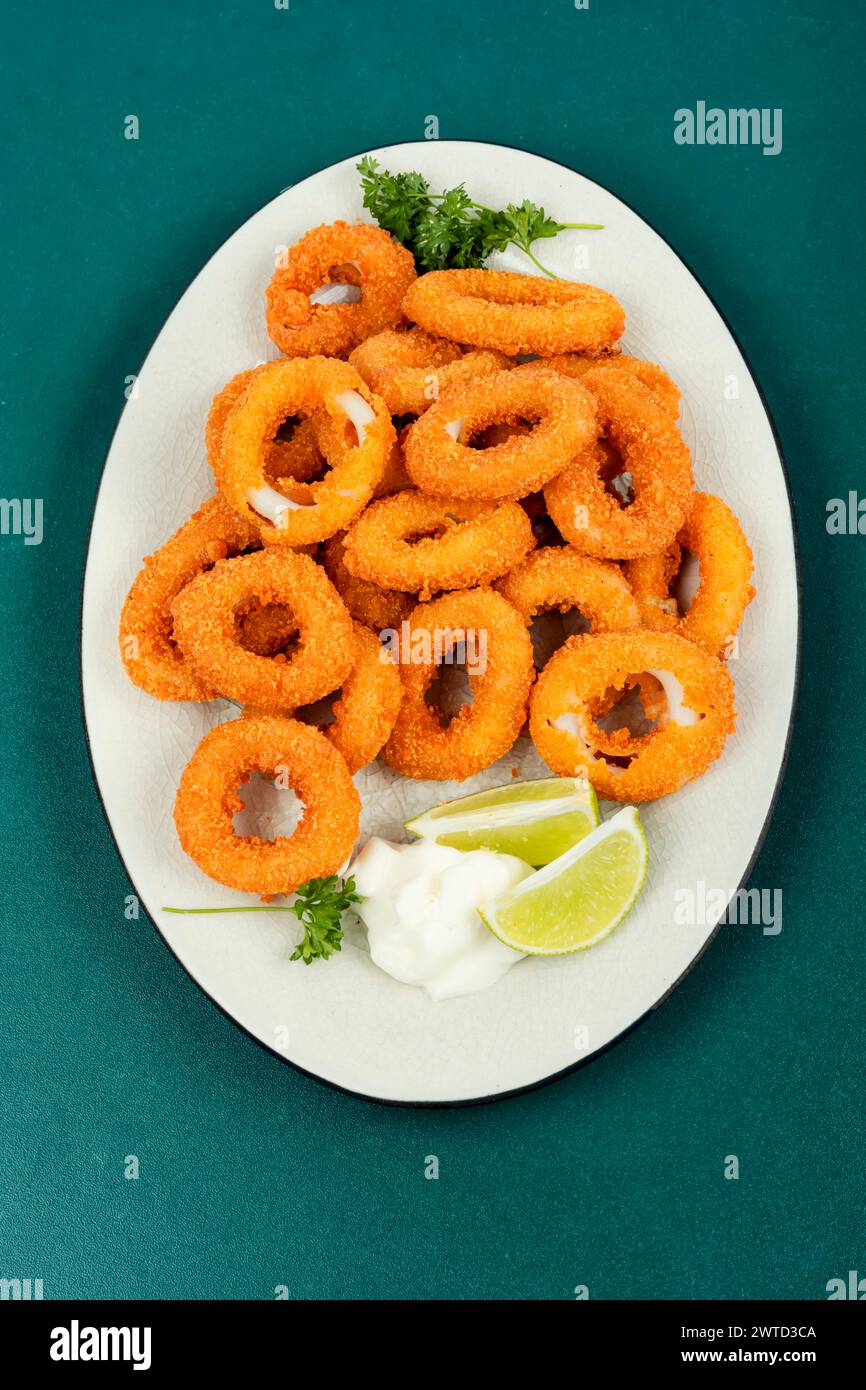 Baked breaded calamari rings served with lime. Top view Stock Photo - Alamy