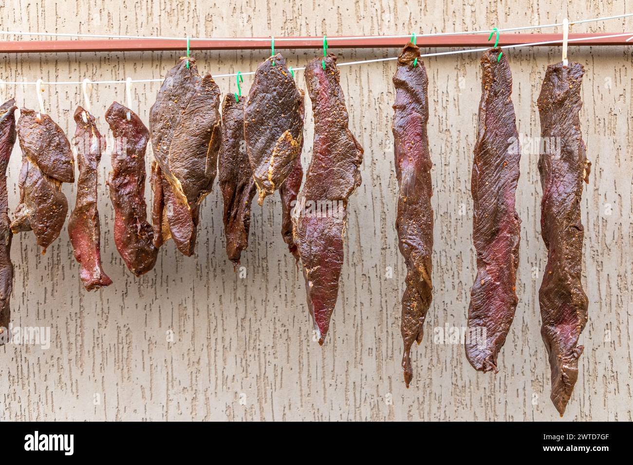 Selection of raw beef pieces hanging outside to dry to become a popular ...