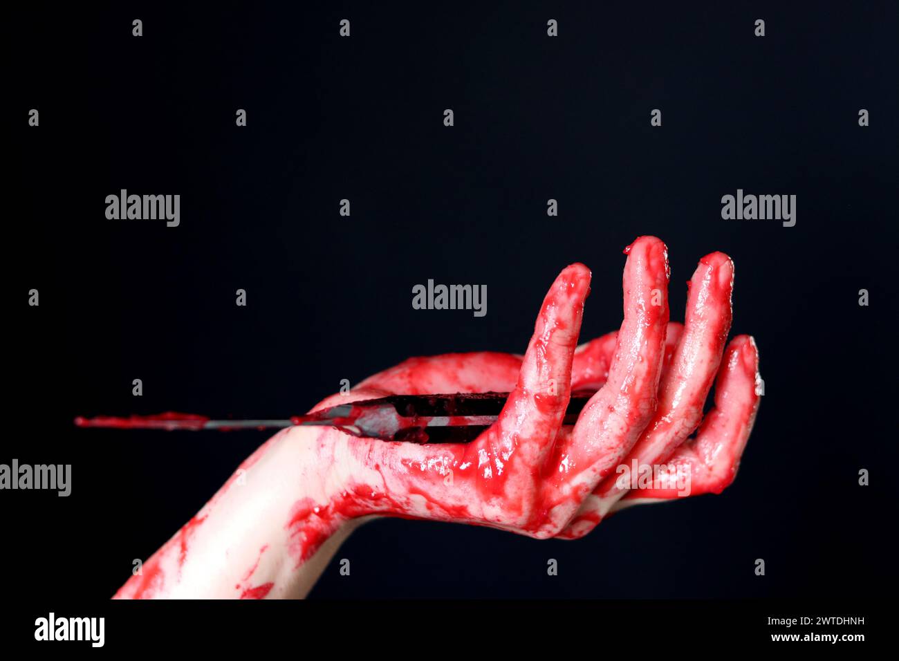 Bloody hand holding a knife with blood on a black background. Domestic ...
